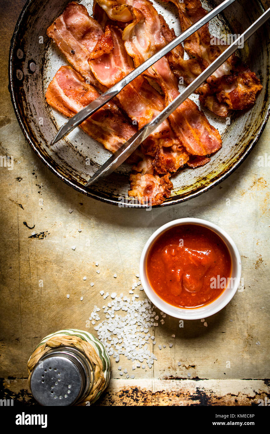 Fried bacon with sauce and salt. On an old rustic background Stock ...