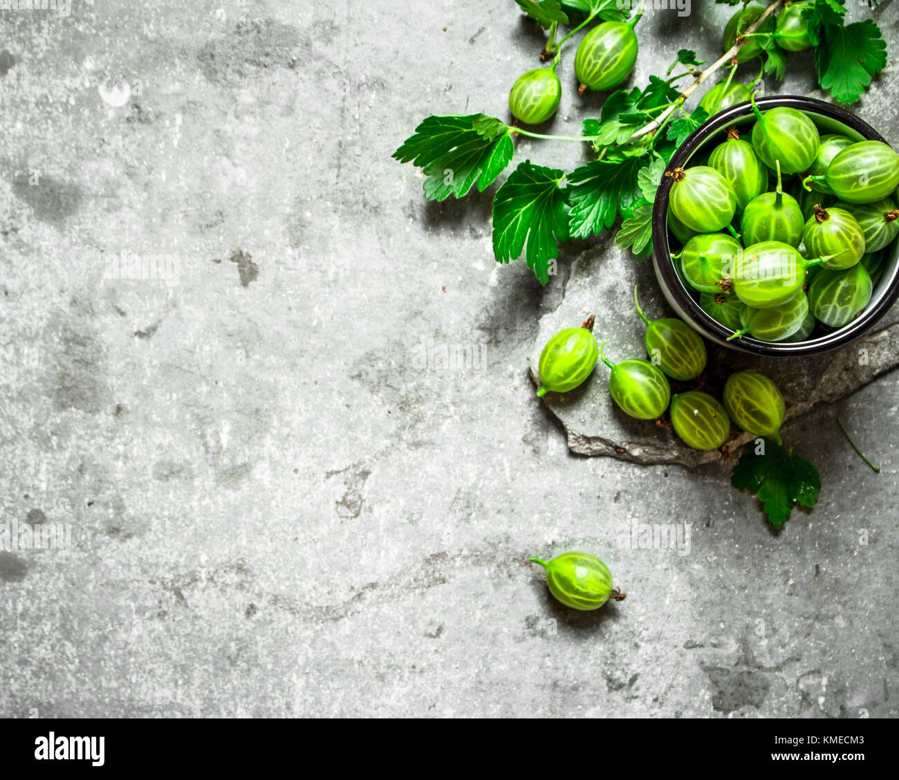 Gooseberries and leaves in a mug. On the stone table Stock Photo - Alamy