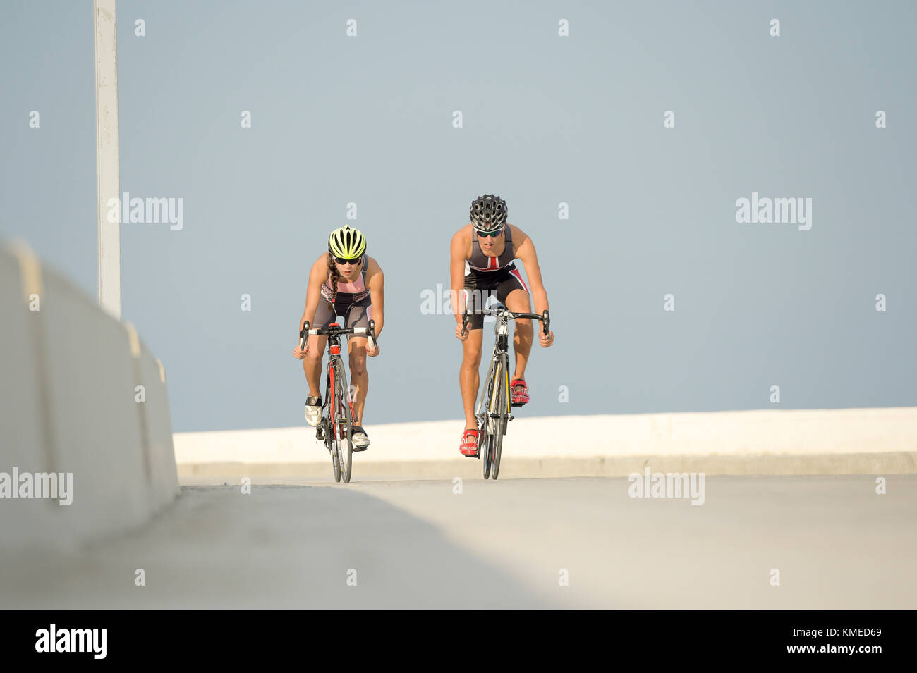 Two cyclists riding bicycles against clear sky during triathlon race ...