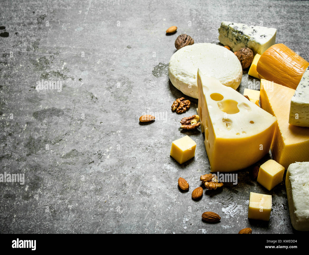 Pieces of different cheeses with walnuts. On the stone table Stock ...