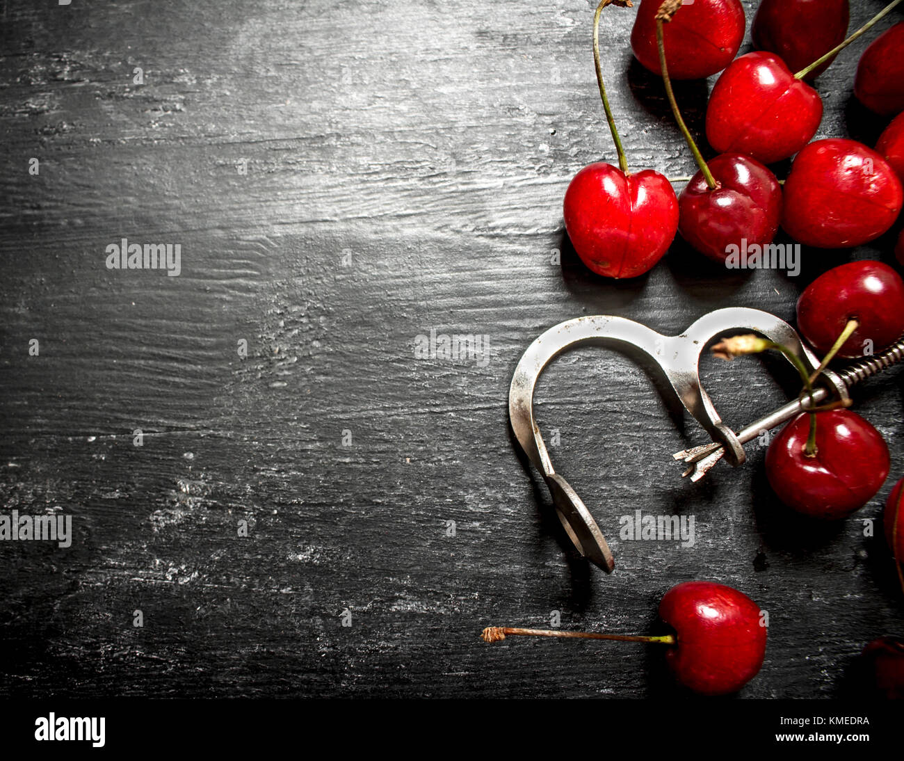 Red cherry with a metal tool to cherry. On a black wooden background ...
