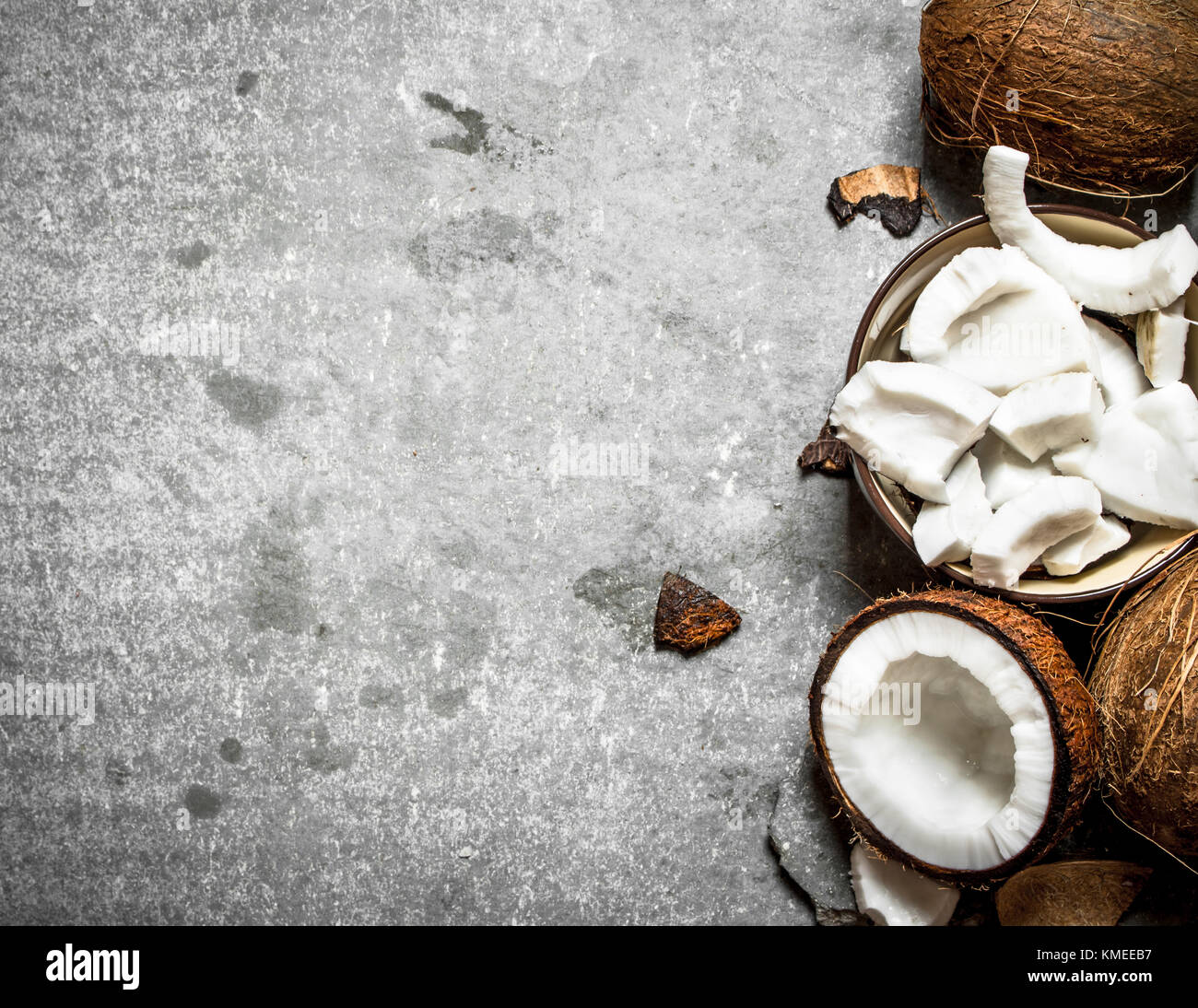 Coconut pulp in a bowl and whole coconuts. On a stone background Stock ...