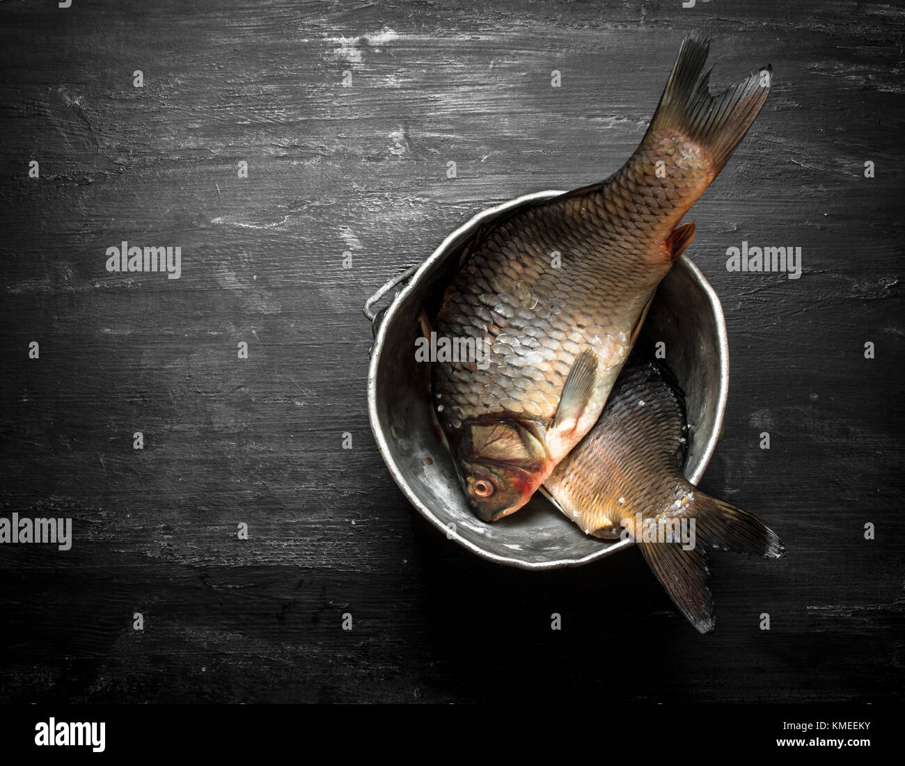 Fish in the old pot. On a black wooden background Stock Photo - Alamy