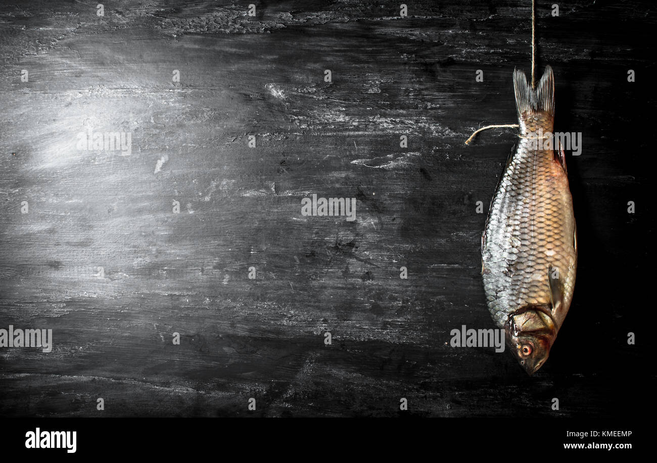 Raw fish hanging on a rope. On a black wooden background Stock Photo ...