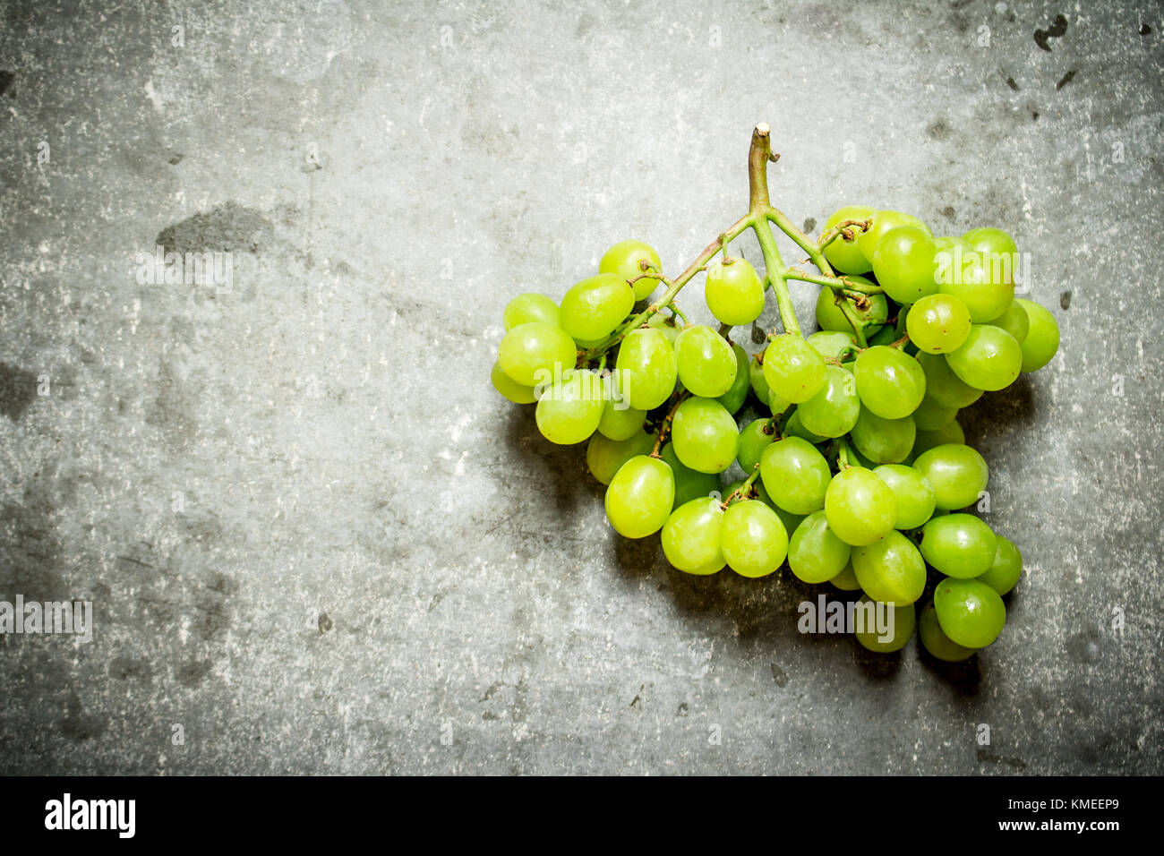 Branch of white grapes. On the stone table Stock Photo - Alamy
