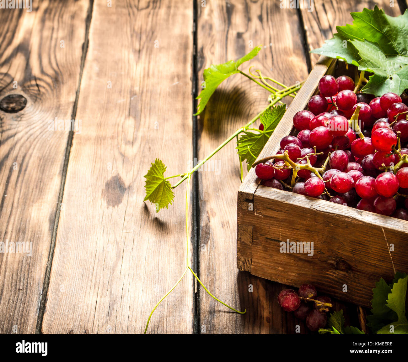 Red grapes with vine branches in the box. On wooden background Stock ...
