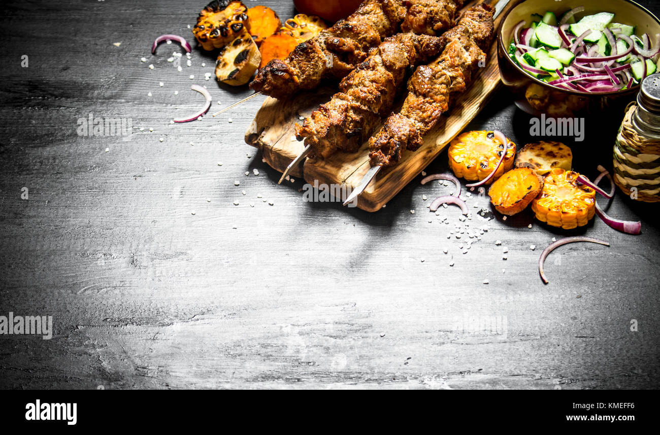 Shish kebab on skewers with grilled vegetables and fresh salad. On the ...