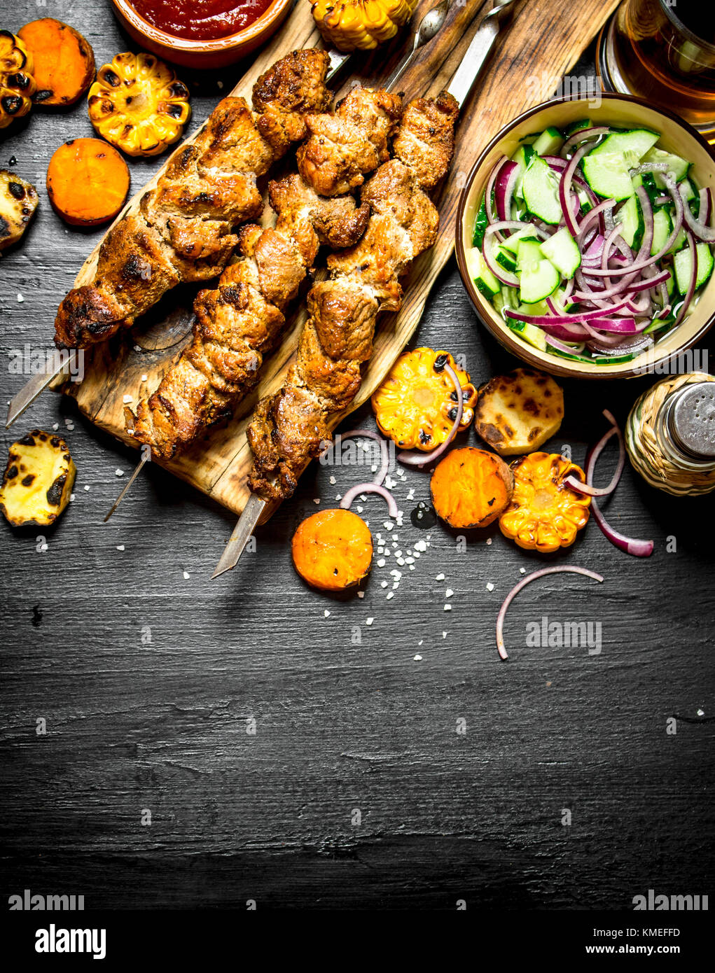 Shish kebab on skewers with grilled vegetables and fresh salad. On the ...