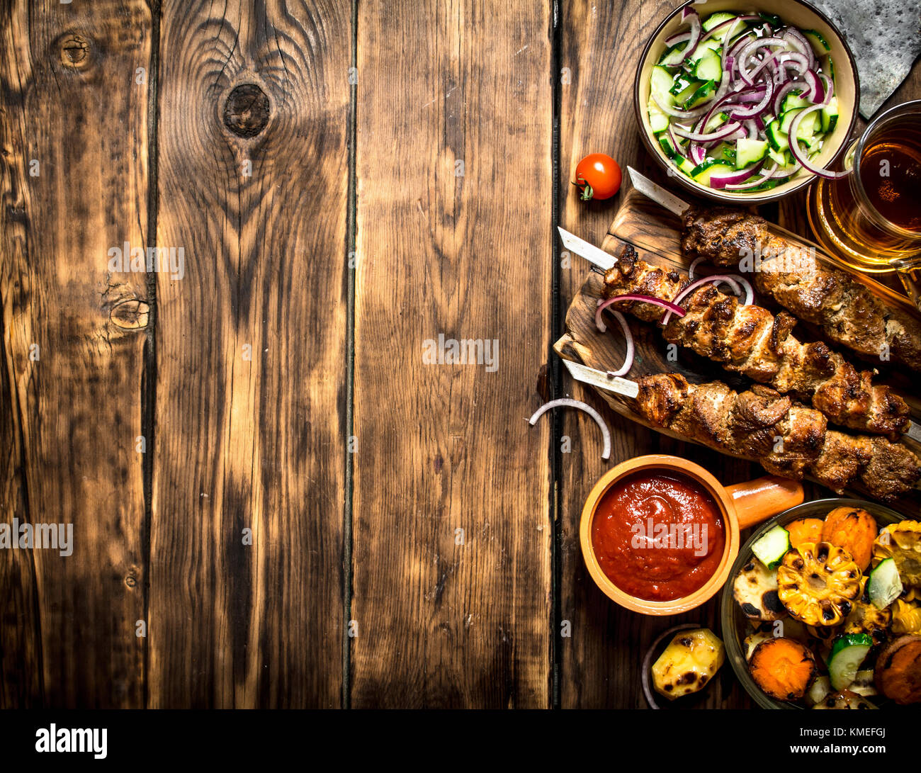 Kebab with tomato sauce and roasted vegetables. On wooden background ...