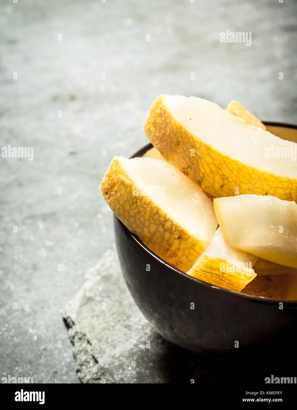 Sliced melon in a bowl. On a stone background Stock Photo - Alamy