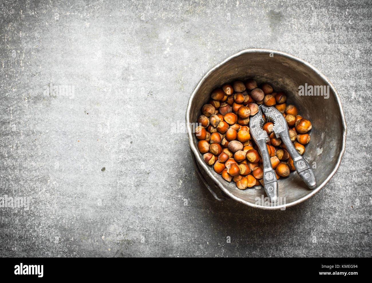 Hazelnuts with Nutcracker in the old pot. On the stone table Stock ...