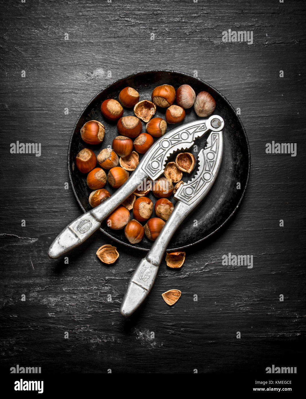 Hazelnuts with Nutcracker on the old plate. On the black wooden table ...