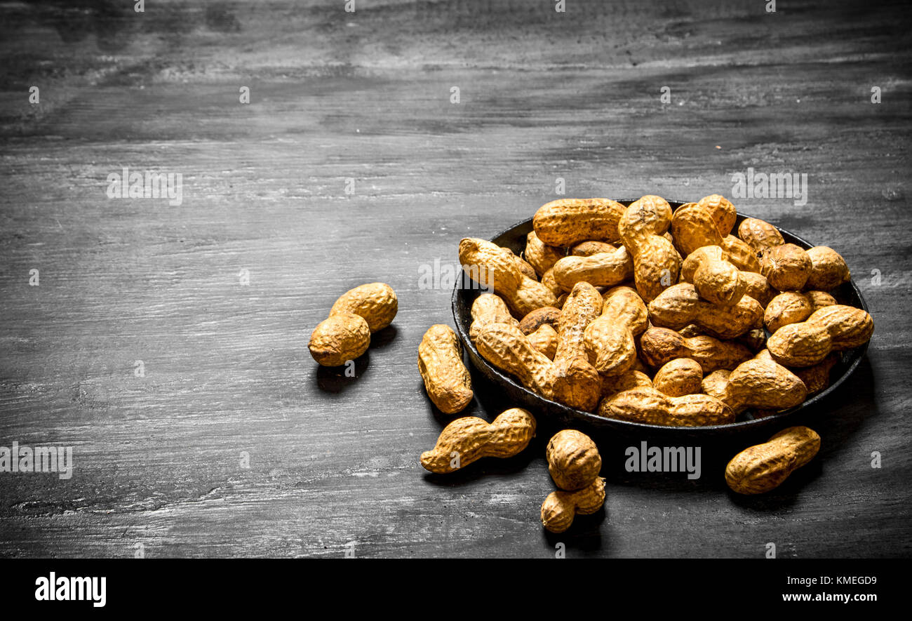 Peanuts in the old plate. On the black wooden table Stock Photo - Alamy