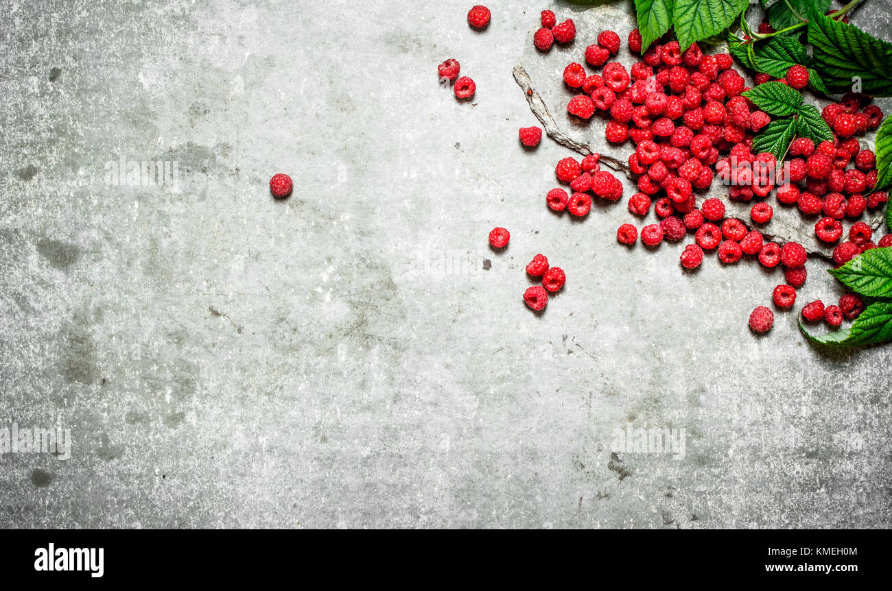 Red raspberry with leaves. On a stone background Stock Photo - Alamy