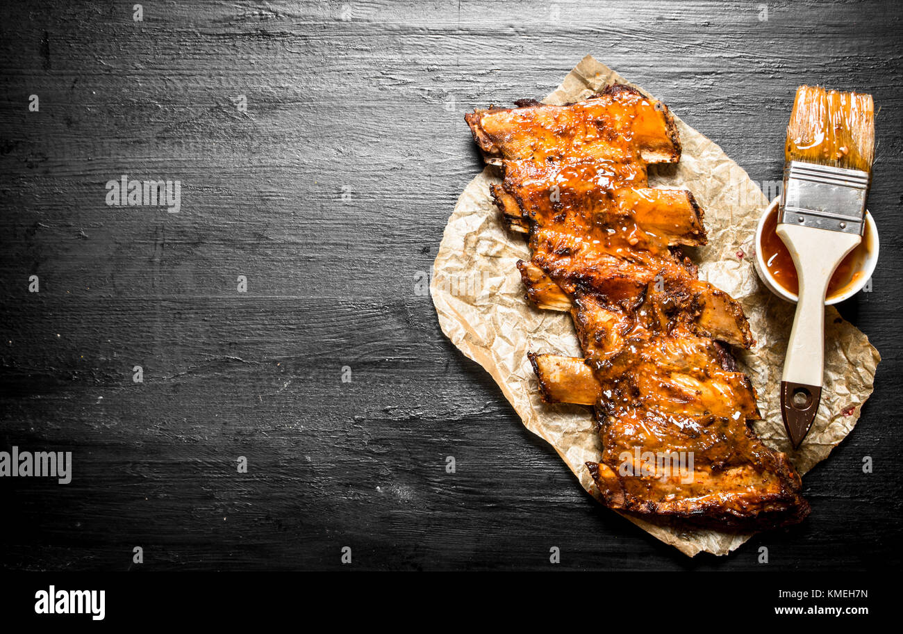 Pork ribs grilled with a spicy sauce and a brush. On the black chalk ...