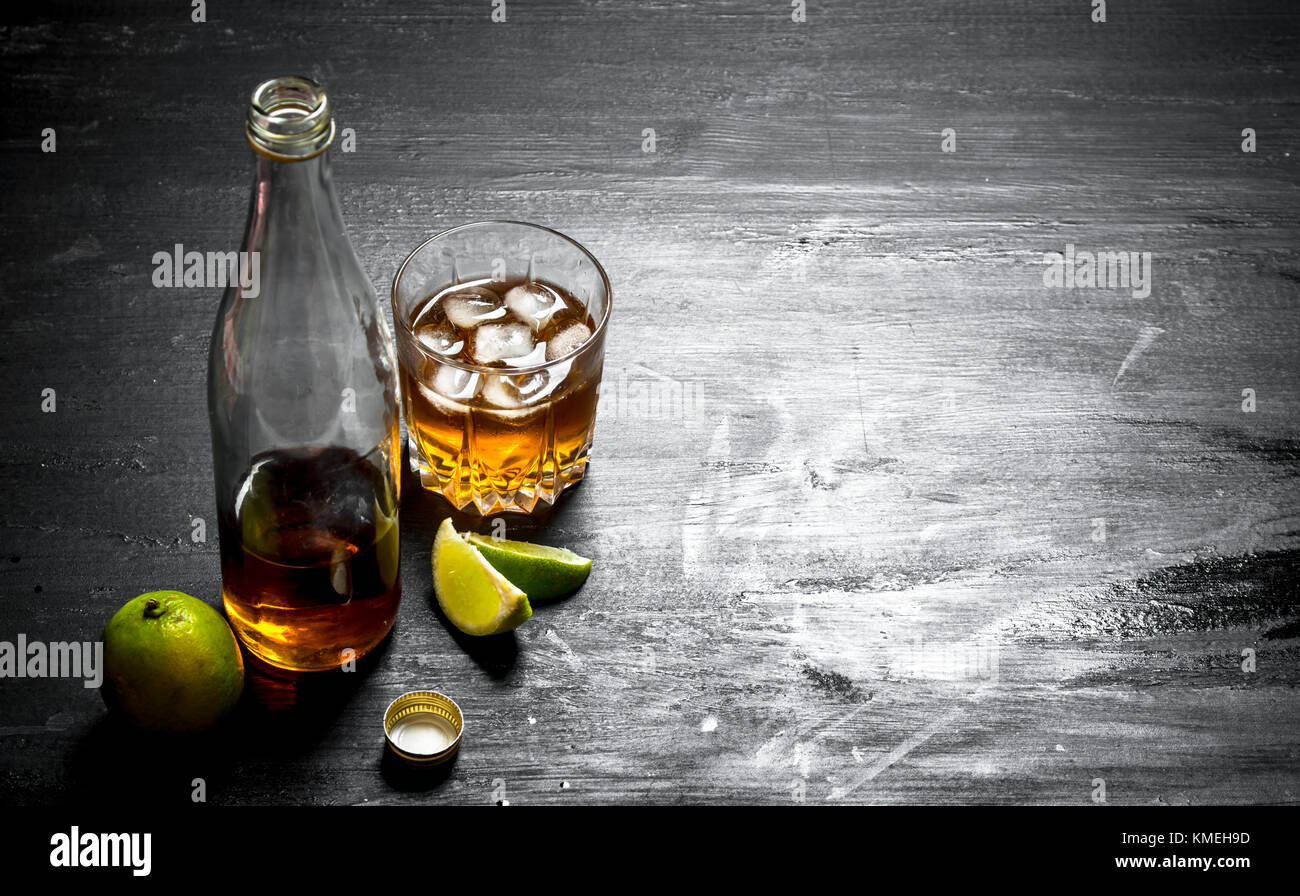 bottle of rum with lime. On a black wooden background Stock Photo - Alamy