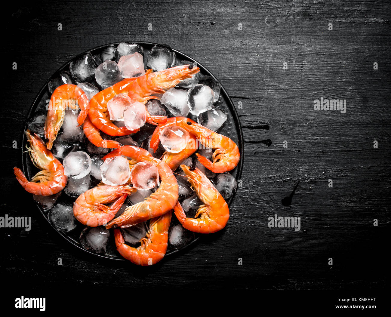 Shrimp with ice on the plate. On the black chalkboard Stock Photo - Alamy