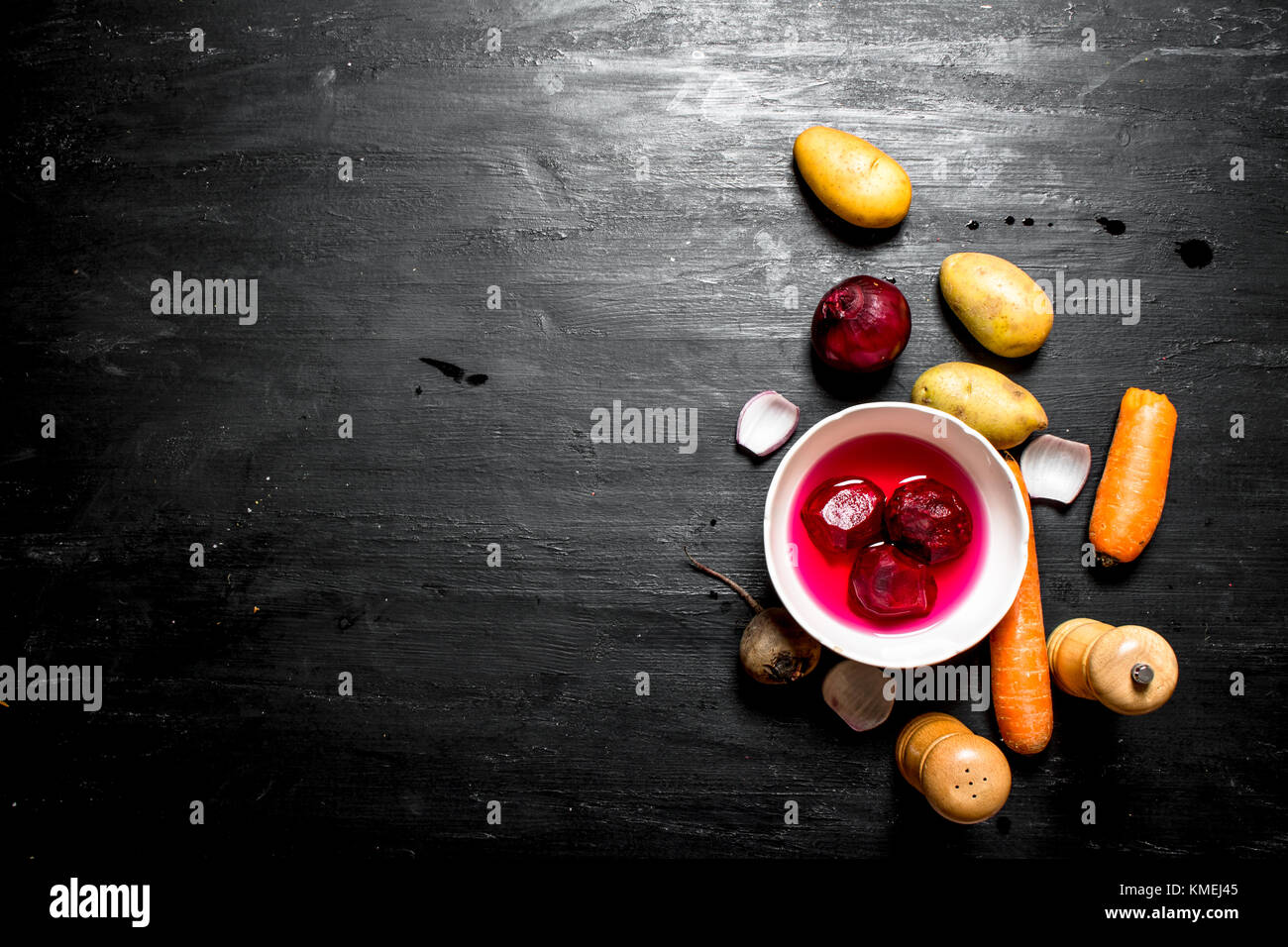 Preparation of soup from fresh vegetables. On a black wooden background ...