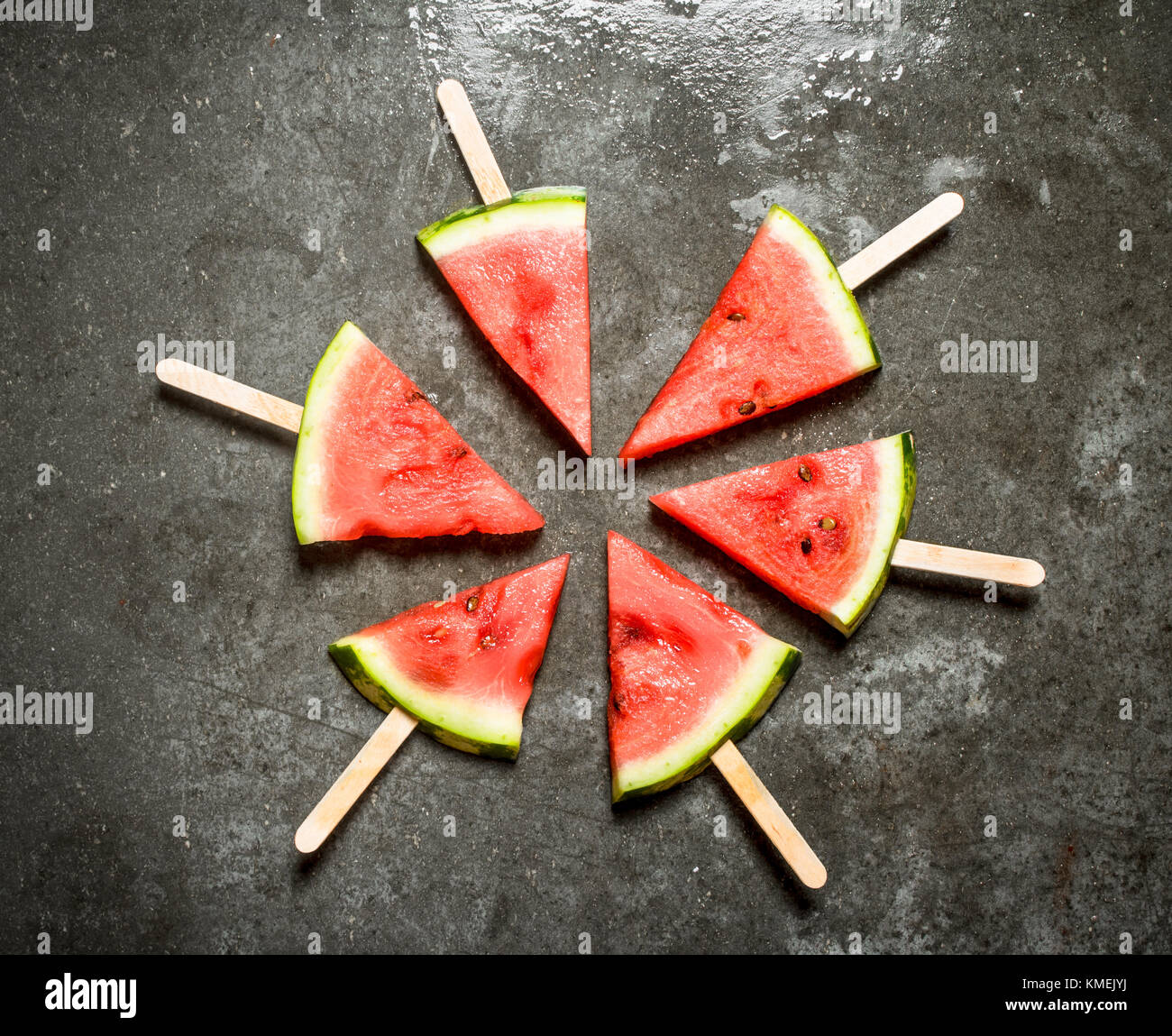 Slices of watermelon on wooden sticks. On the stone table Stock Photo ...