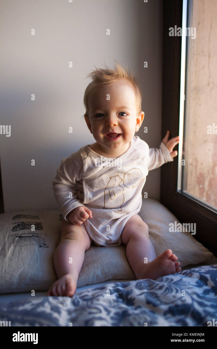 Portrait of a little boy who is sitting in the window and smiling ...