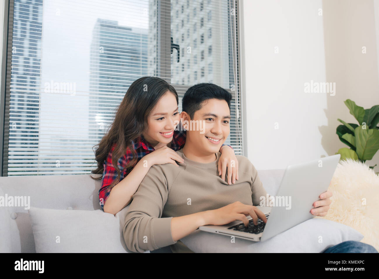 Cheerful asian couple searching something on laptop at home Stock Photo ...