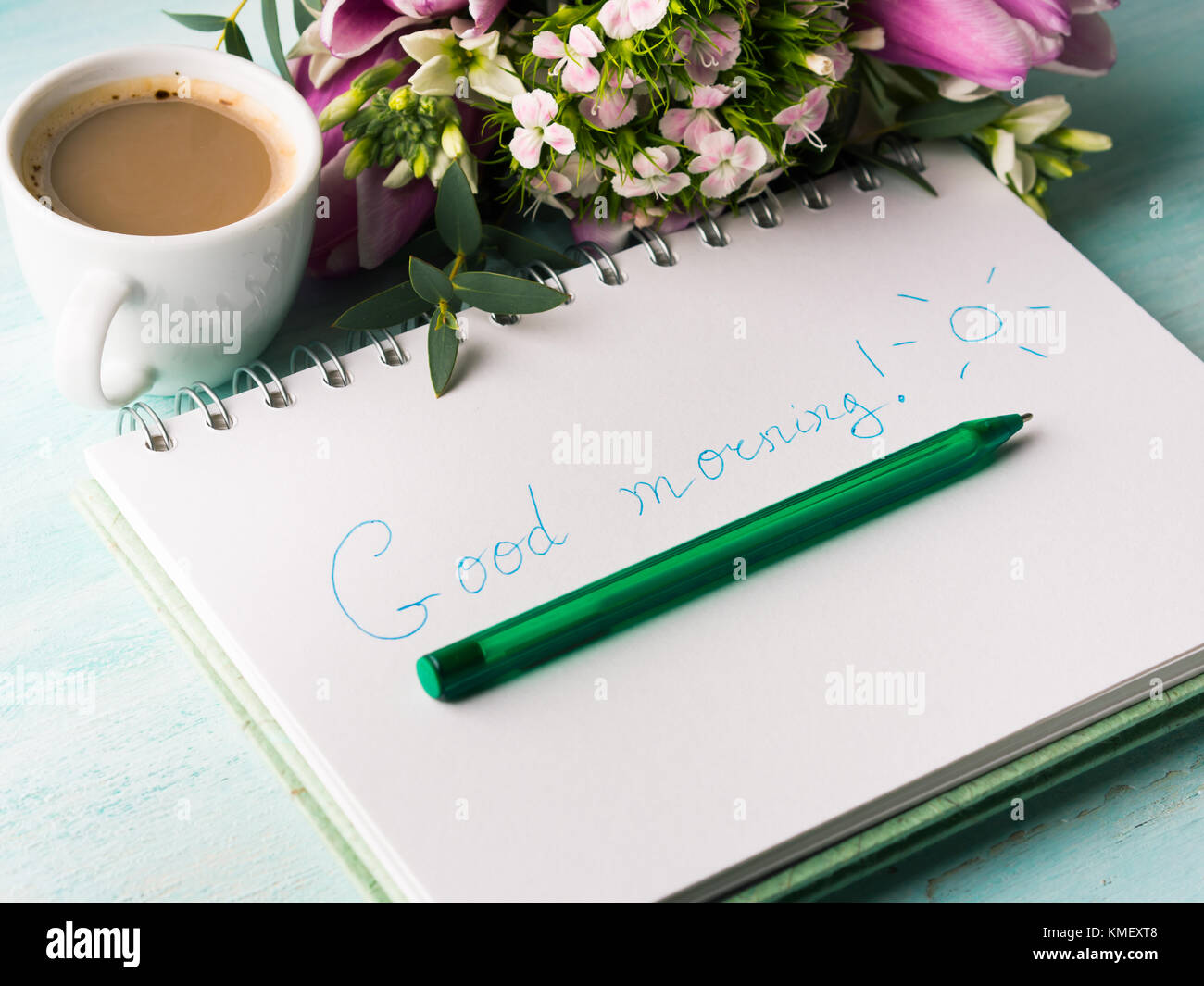 Wishing good morning hand written on notebook page and cup of coffee ...