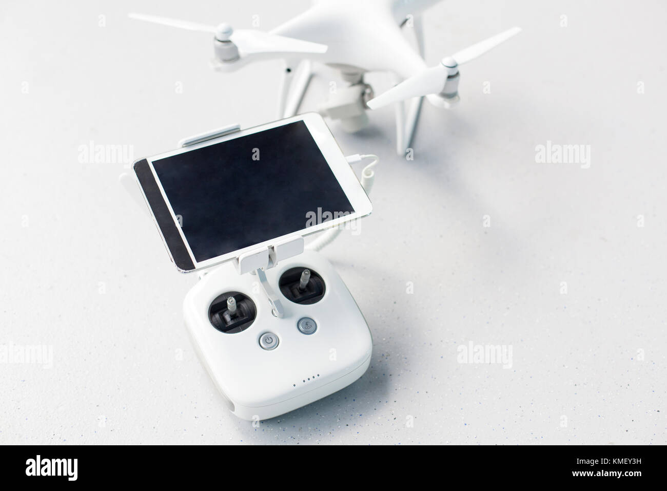 Drone with a remote control and a tablet on it on a gray concrete ...