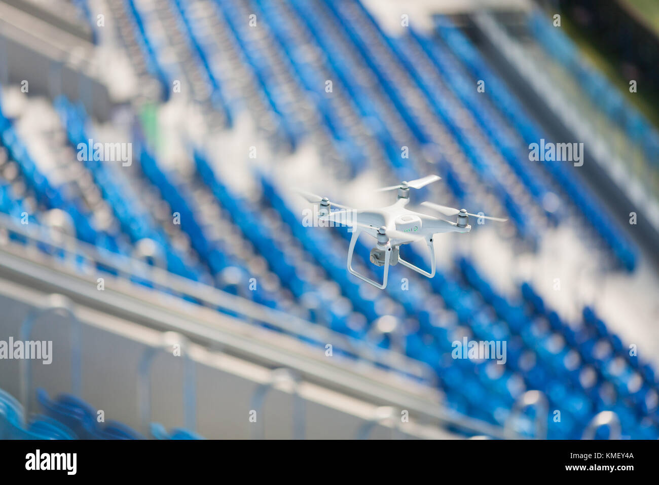 White quadcopter flies over the football stadium and shoots video. The ...