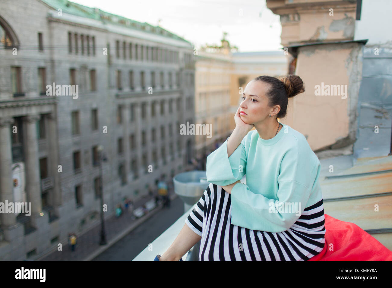 Beautiful lonely girl sitting on the roof in the old town of dreams ...