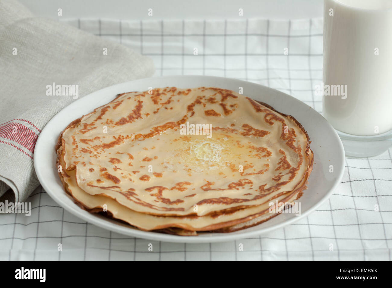 Thin crepes or pancakes with butter and milk on textile background ...