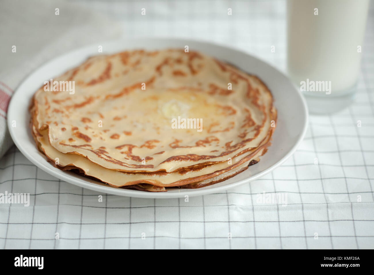 Thin crepes or pancakes with butter and milk on textile background ...