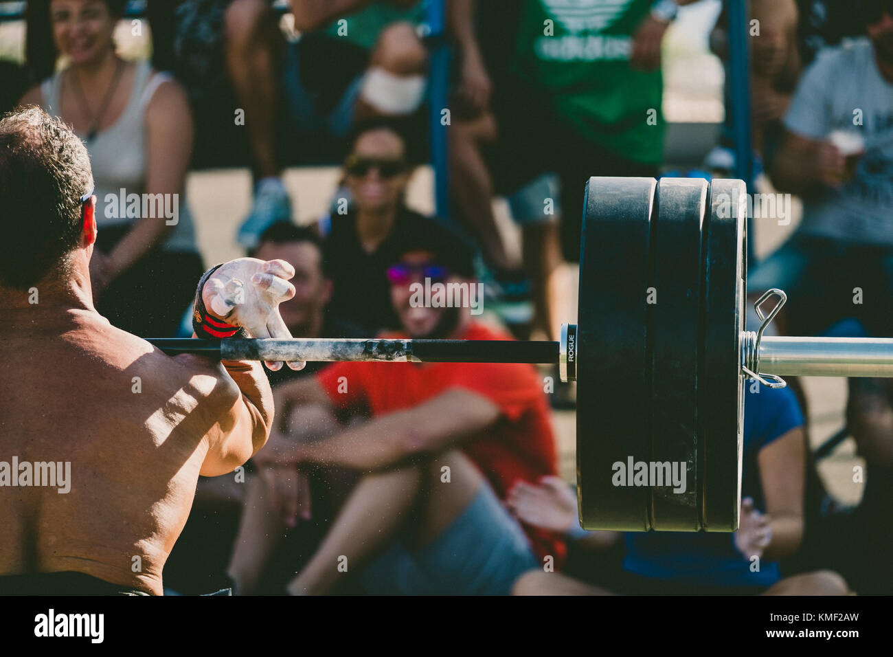 Athlete lifting weights during competition with audience in background ...