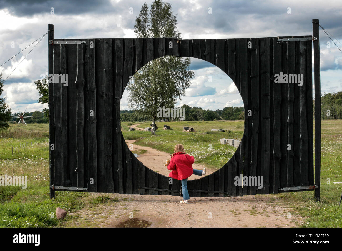 A picture of a child in red jacket stepping through a circle in a gate ...