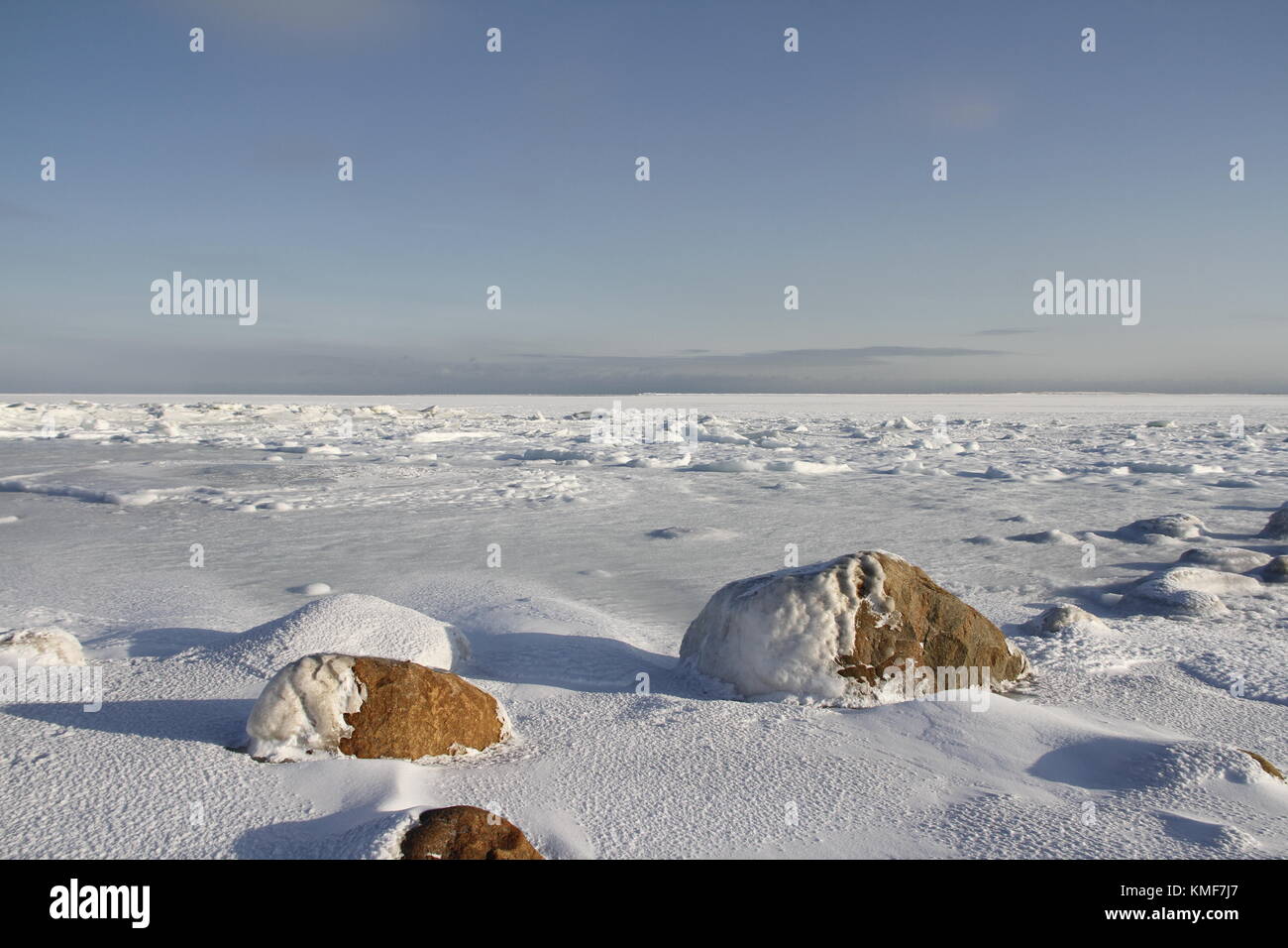 Big rocks under snow and ice with a blue sky in the arctic, north of ...