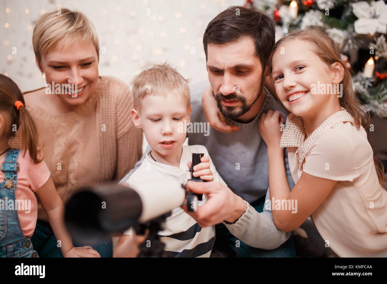 Picture of happy family with telescope on background of Christmas tree ...