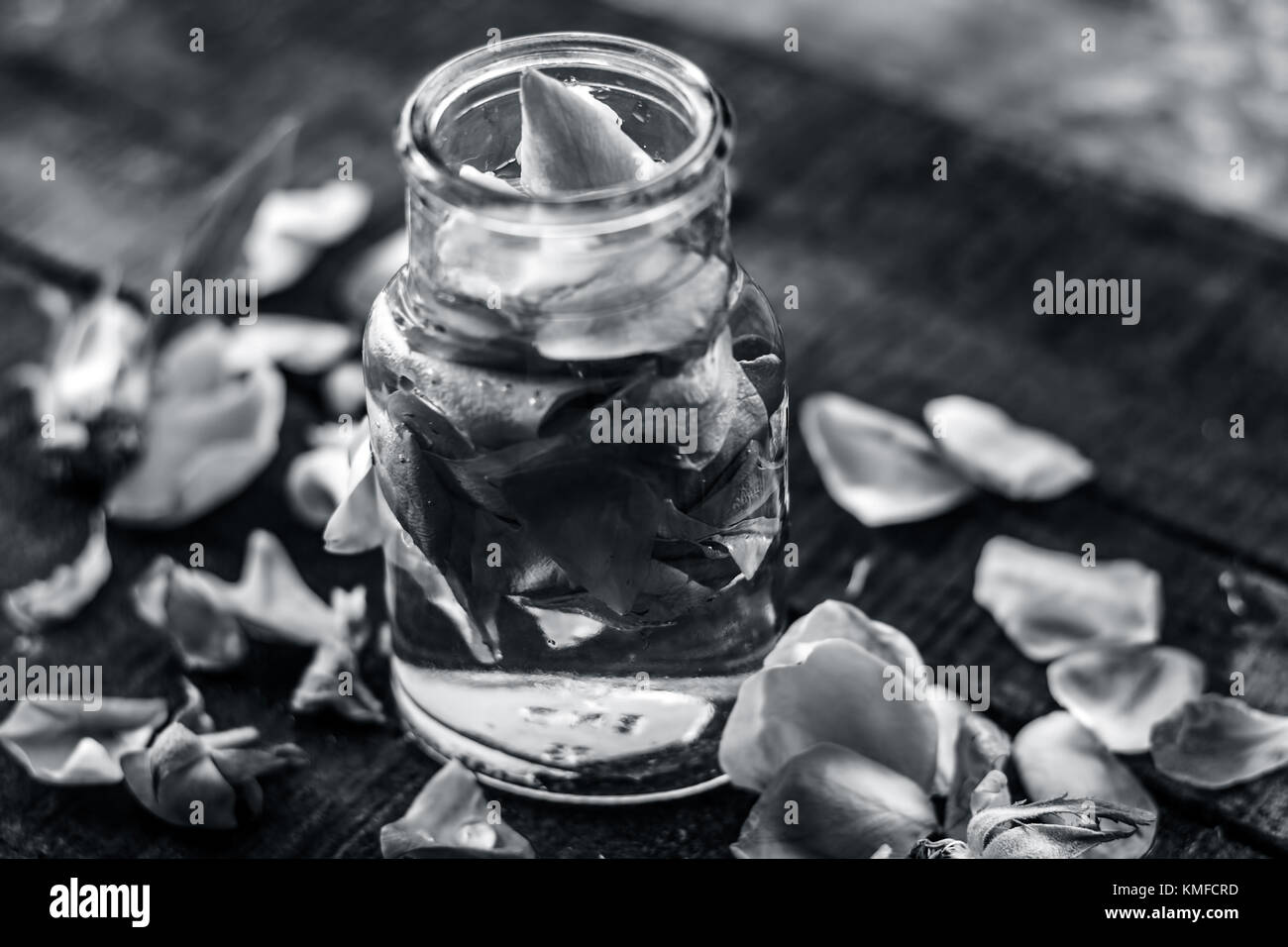 A transparent bottle contains rose water with rose petals in it.Concept ...