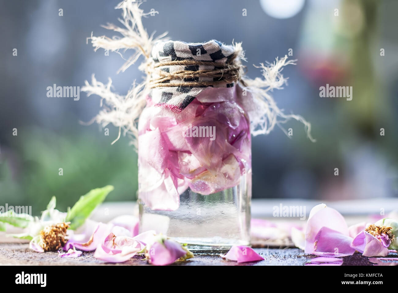 A transparent bottle contains rose water with rose petals in it.Concept ...