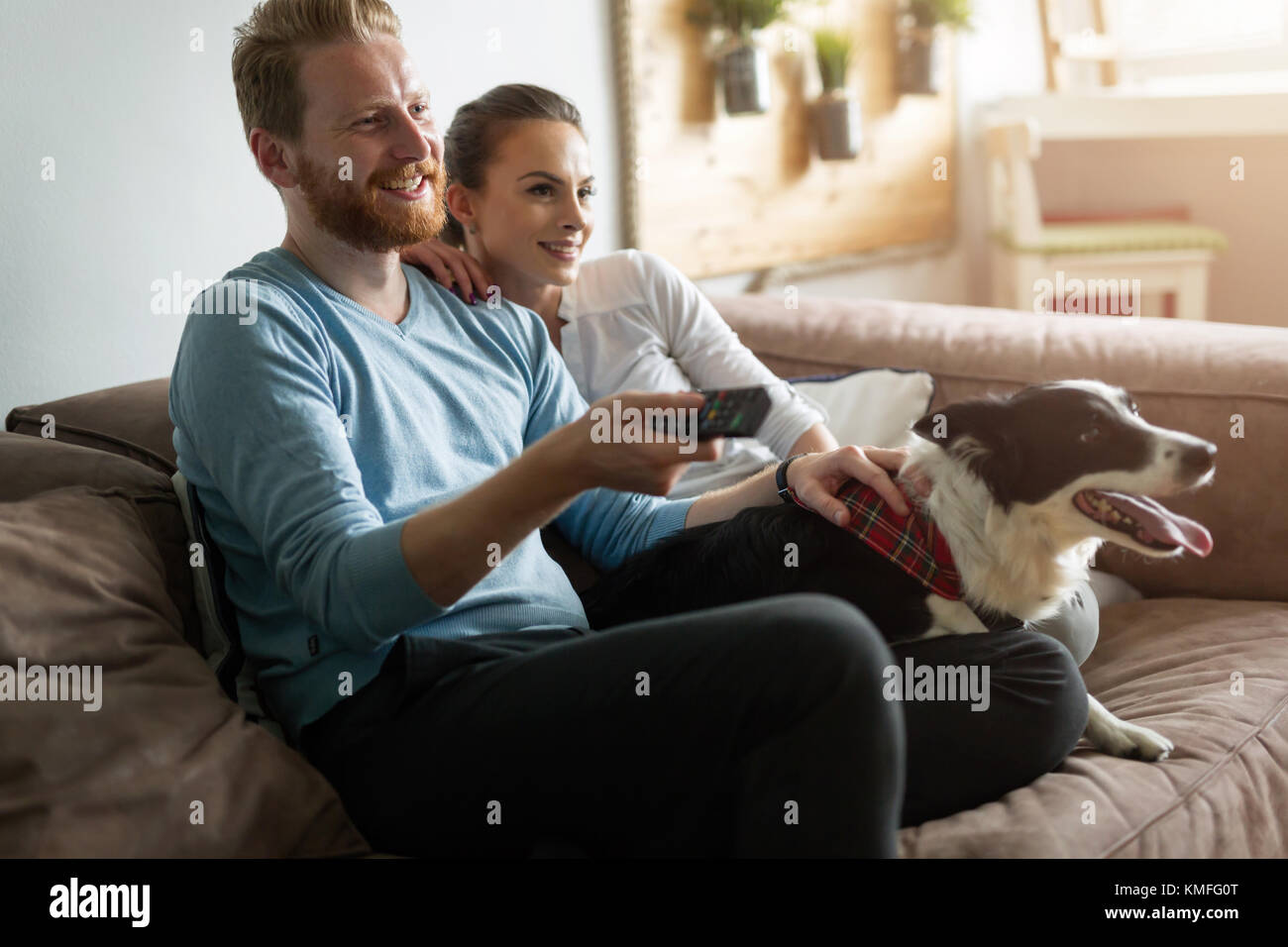 Beautiful couple watching television at home with their dog Stock Photo ...