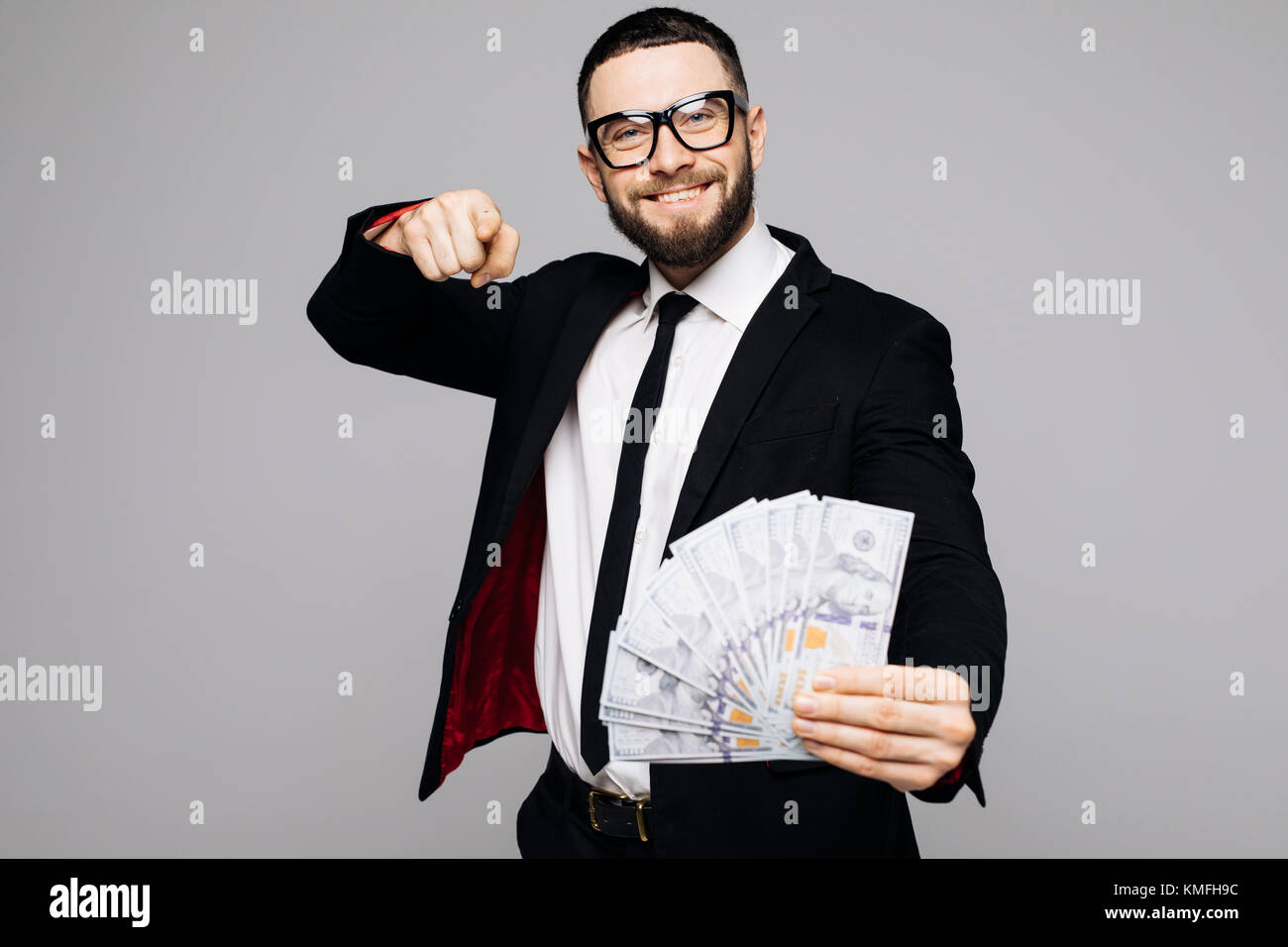 Portrait of smiling successful man in suit and eyewear pointing finger ...