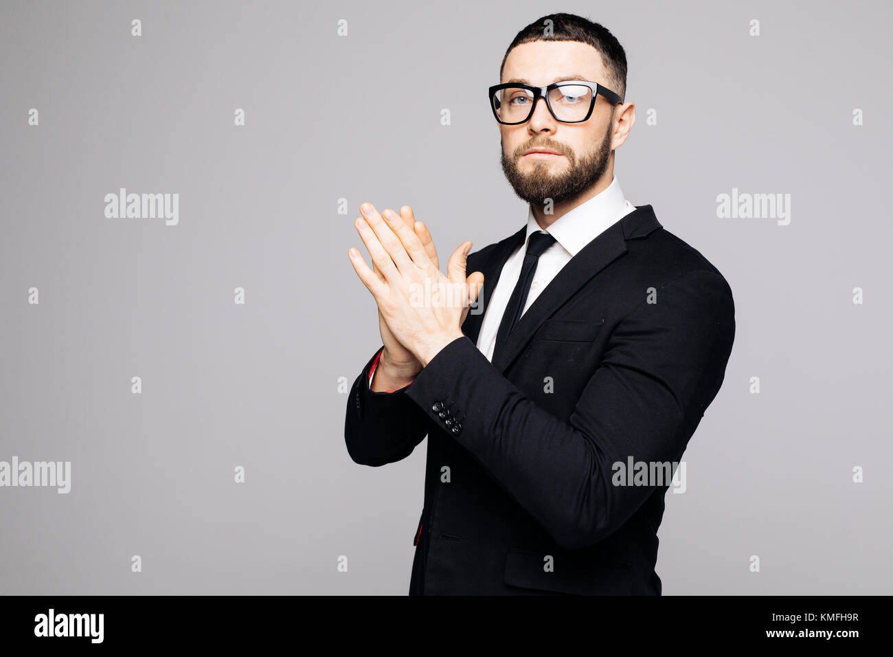 A confident elegant handsome young man standing in front of a grey ...
