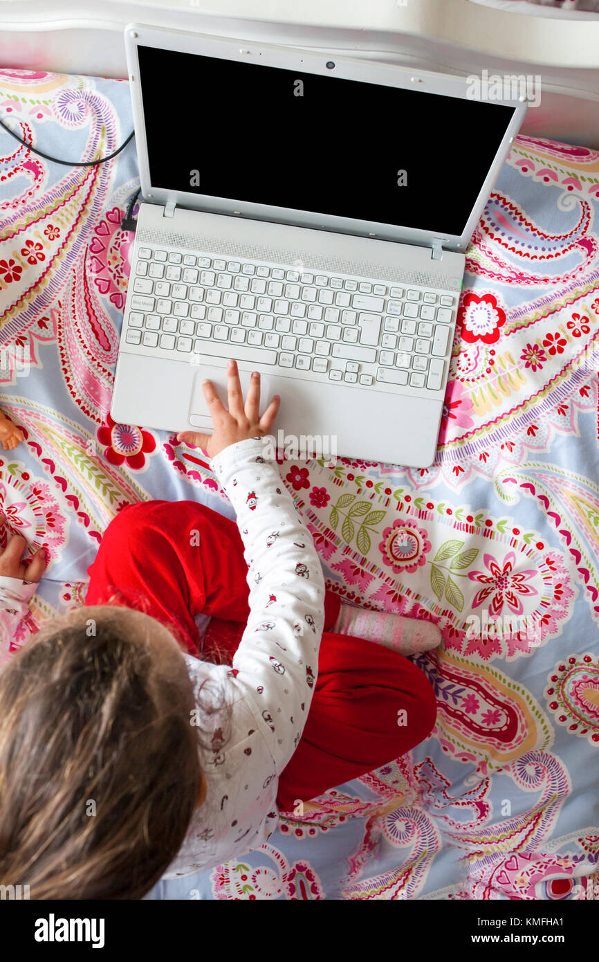 Little girl sitting in bed and playing online games in her bedroom ...