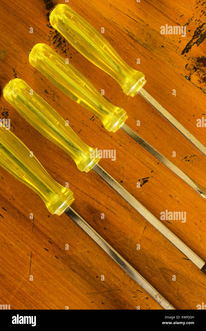 View from above of a 4 yellow screwdrivers set on a wood table arranged ...