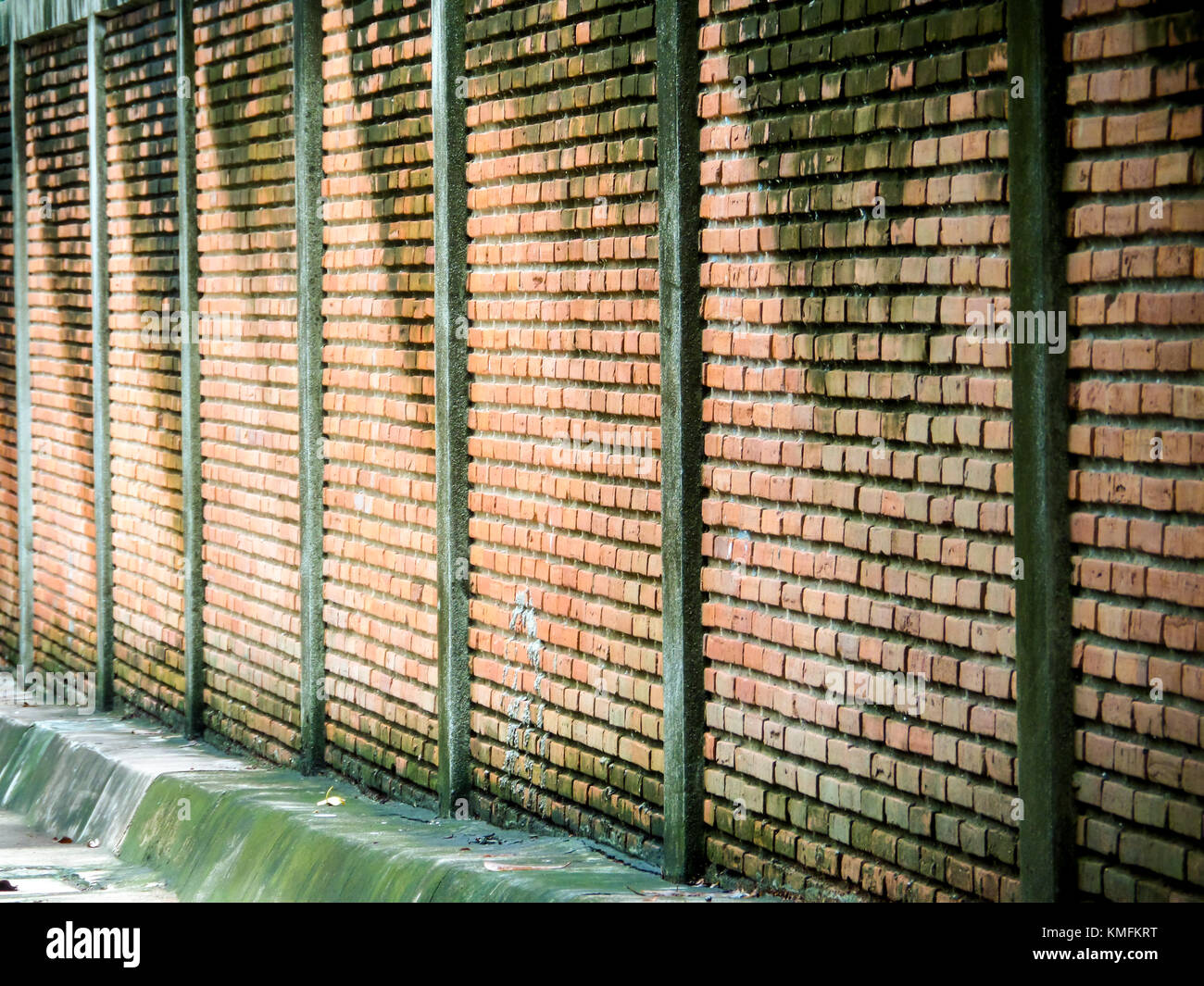 ancient brick wall has erosion and damage by wind and water beside way ...