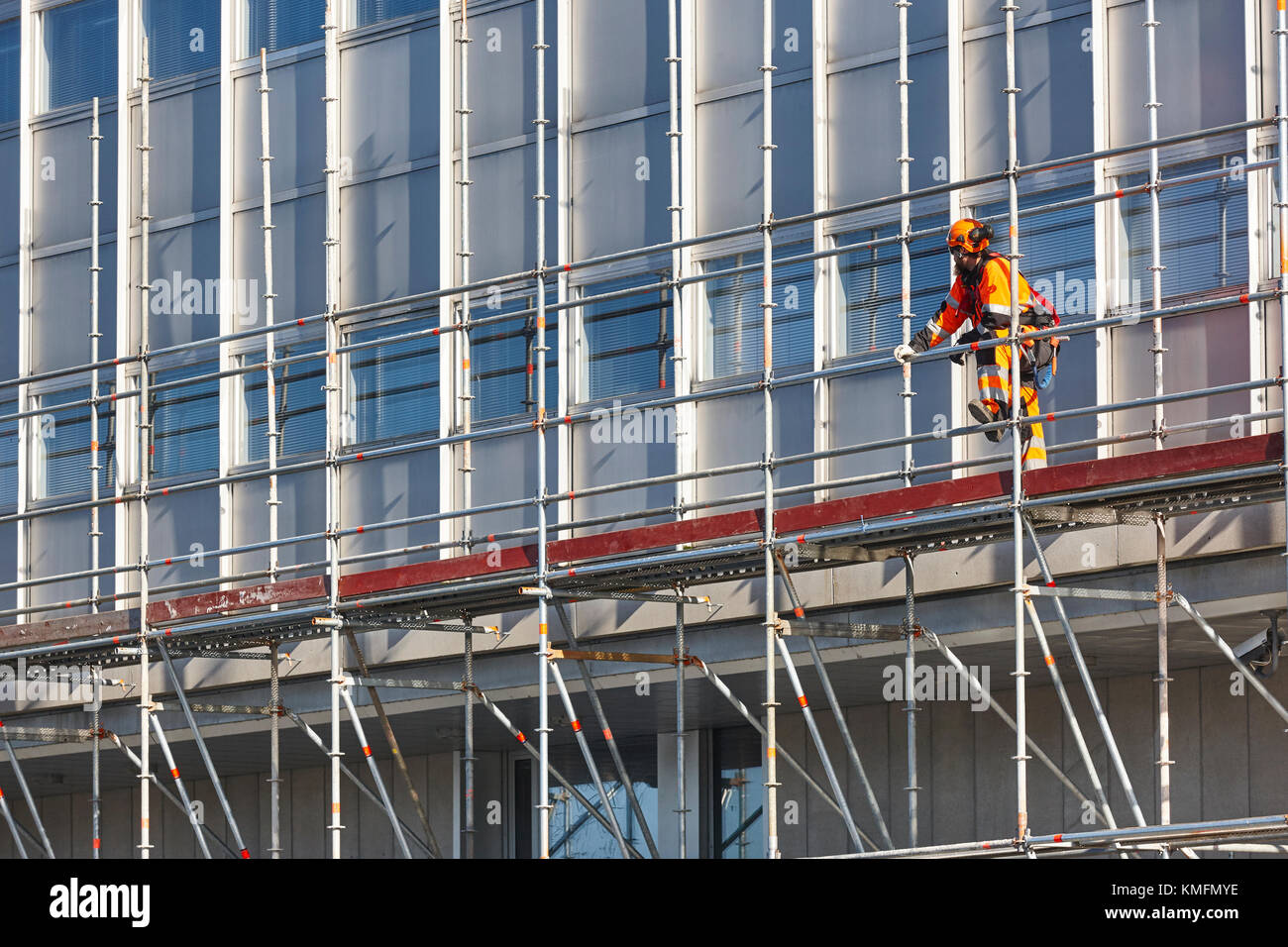 Construction worker mounting a scaffolding structure on a building ...