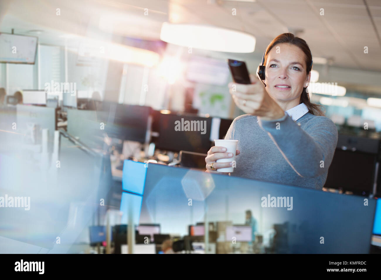 Businesswoman using remote control, drinking coffee in office Stock ...