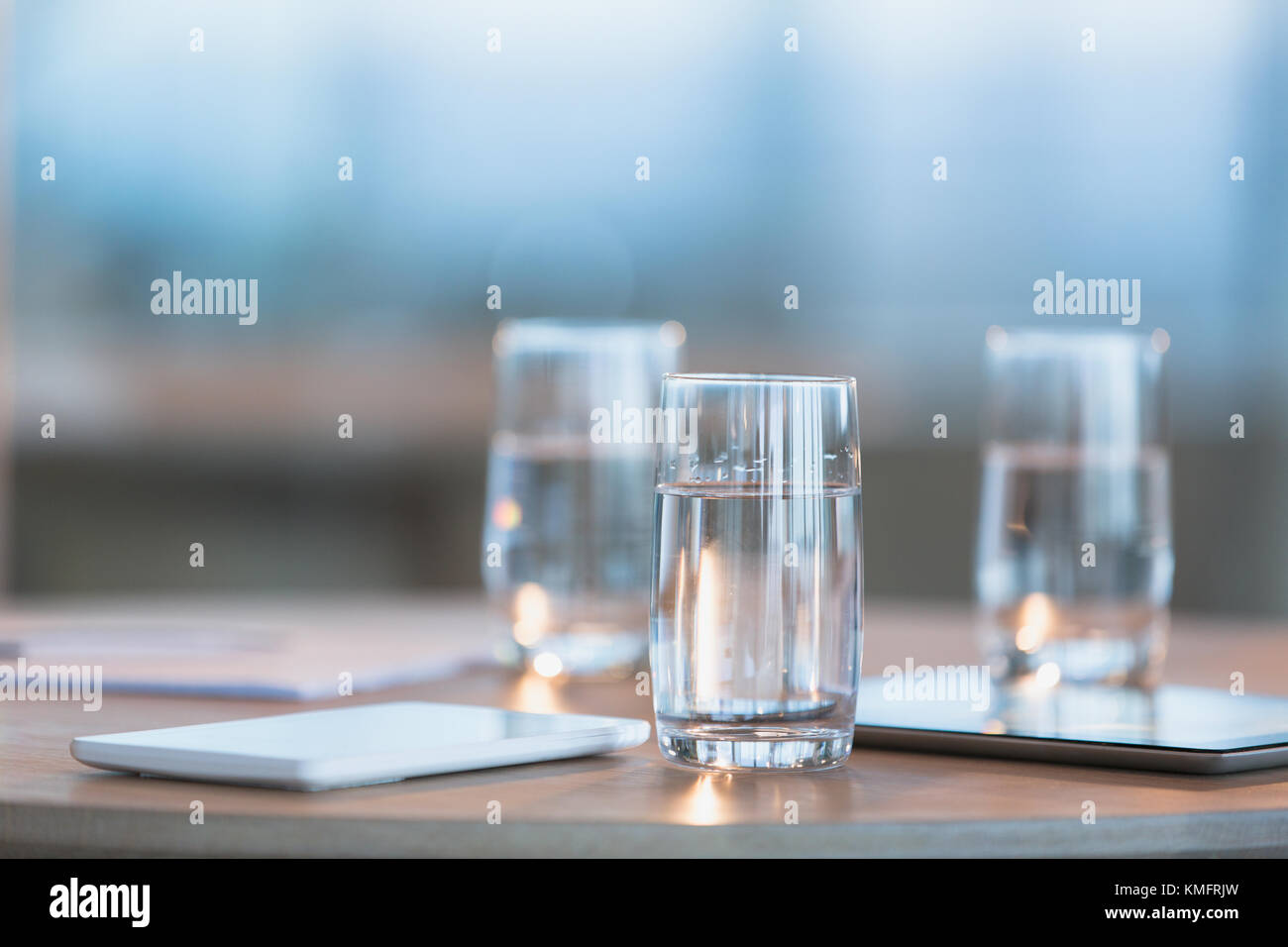 Water in glasses next to digital tablets on table Stock Photo - Alamy