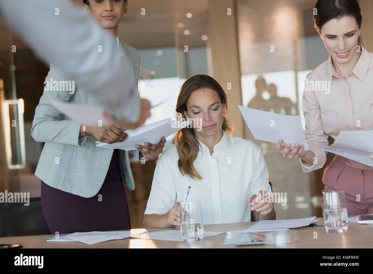 Business people signing and reviewing paperwork in conference room ...