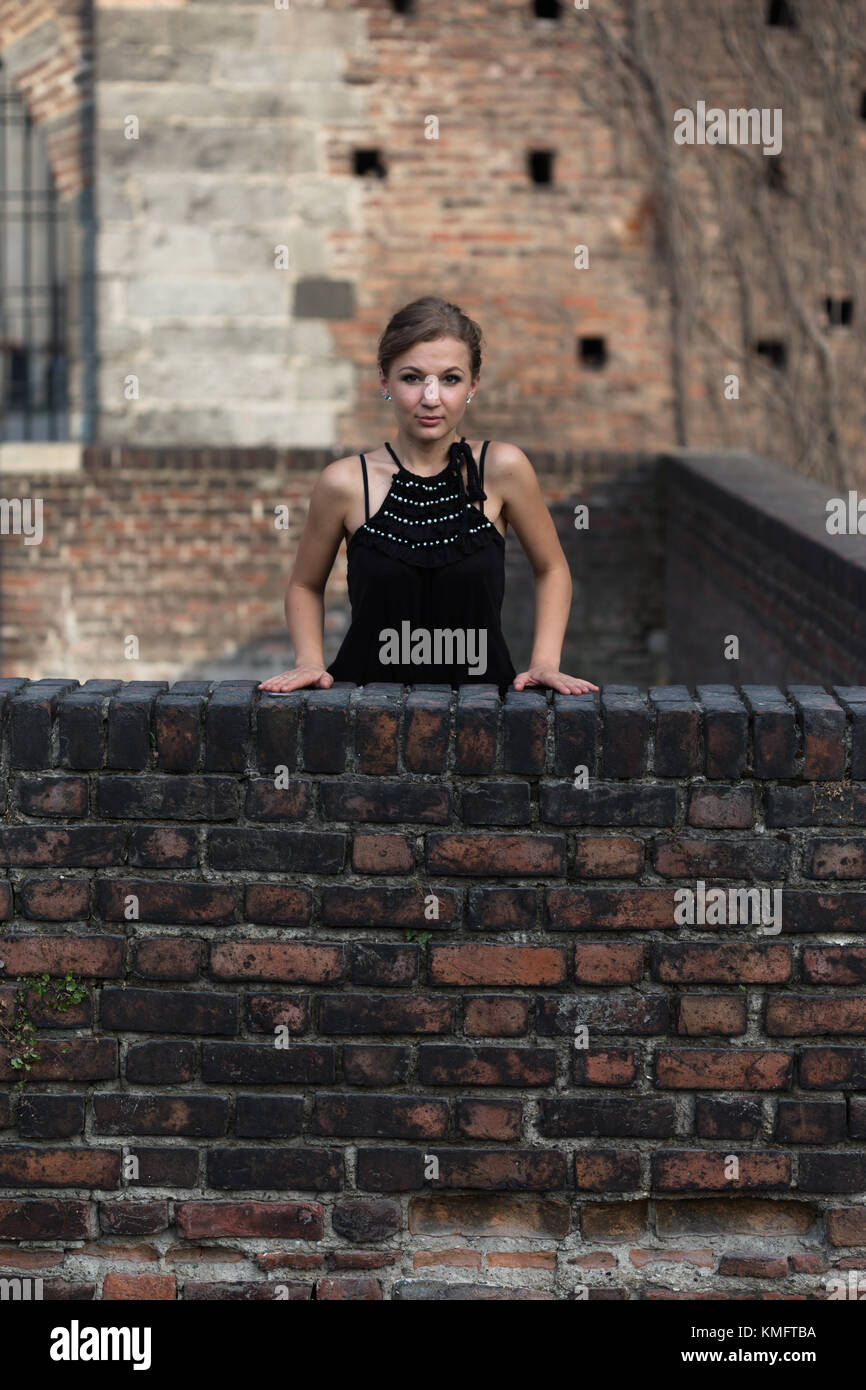 Beautiful young woman dressed in black dress standing in castle Stock ...