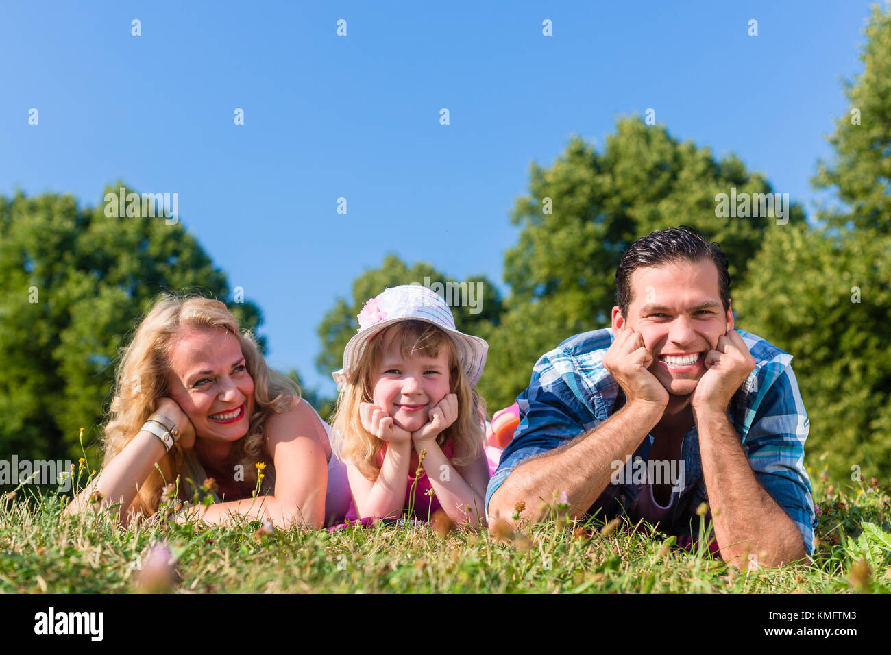 Family lying on meadow, looking to camera, cupping chins in hands Stock ...