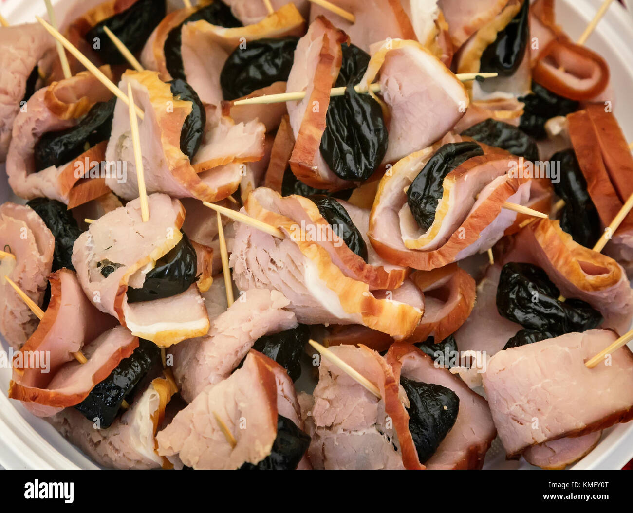Appetizer of meat: slices of ham and prunes glued thin sticks. Presents ...